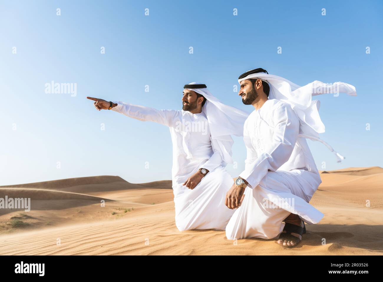 Two middle-eastern men wearing traditional emirati arab kandura bonding ...