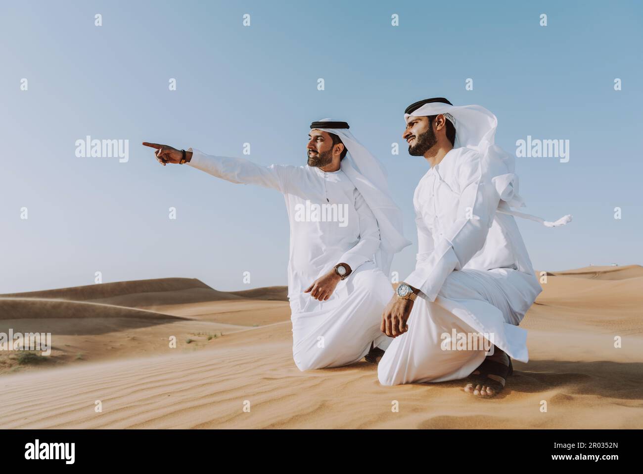 Two middle-eastern men wearing traditional emirati arab kandura bonding ...