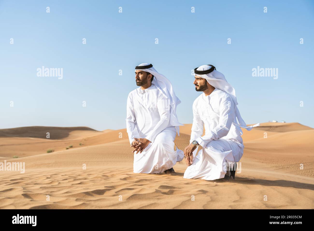 Two middle-eastern men wearing traditional emirati arab kandura bonding ...