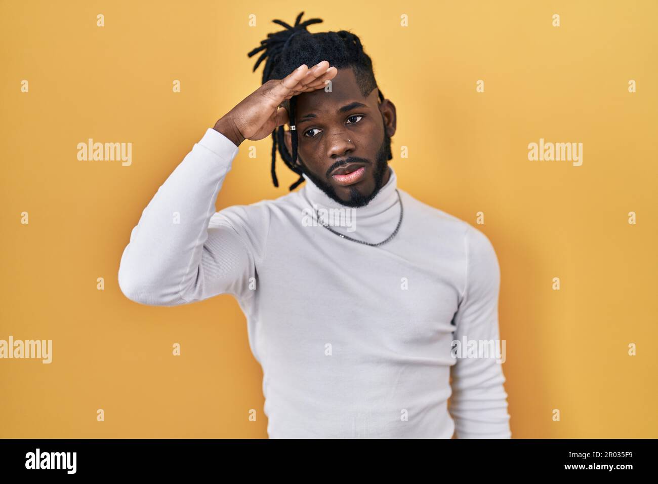 African man with dreadlocks wearing turtleneck sweater over yellow ...