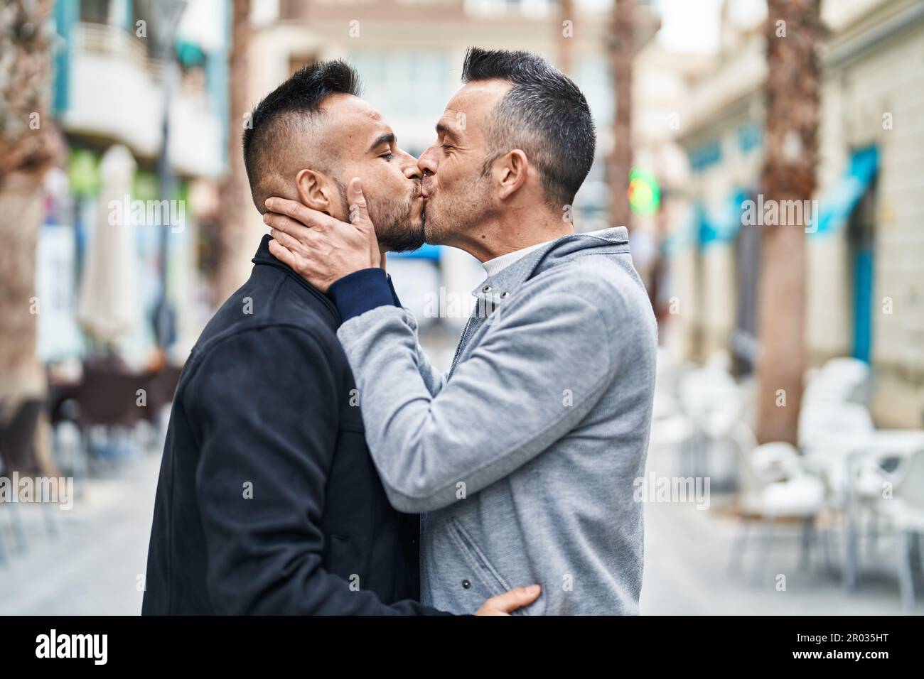 Two men couple hugging each other kissing at coffee shop terrace Stock Photo - Alamy