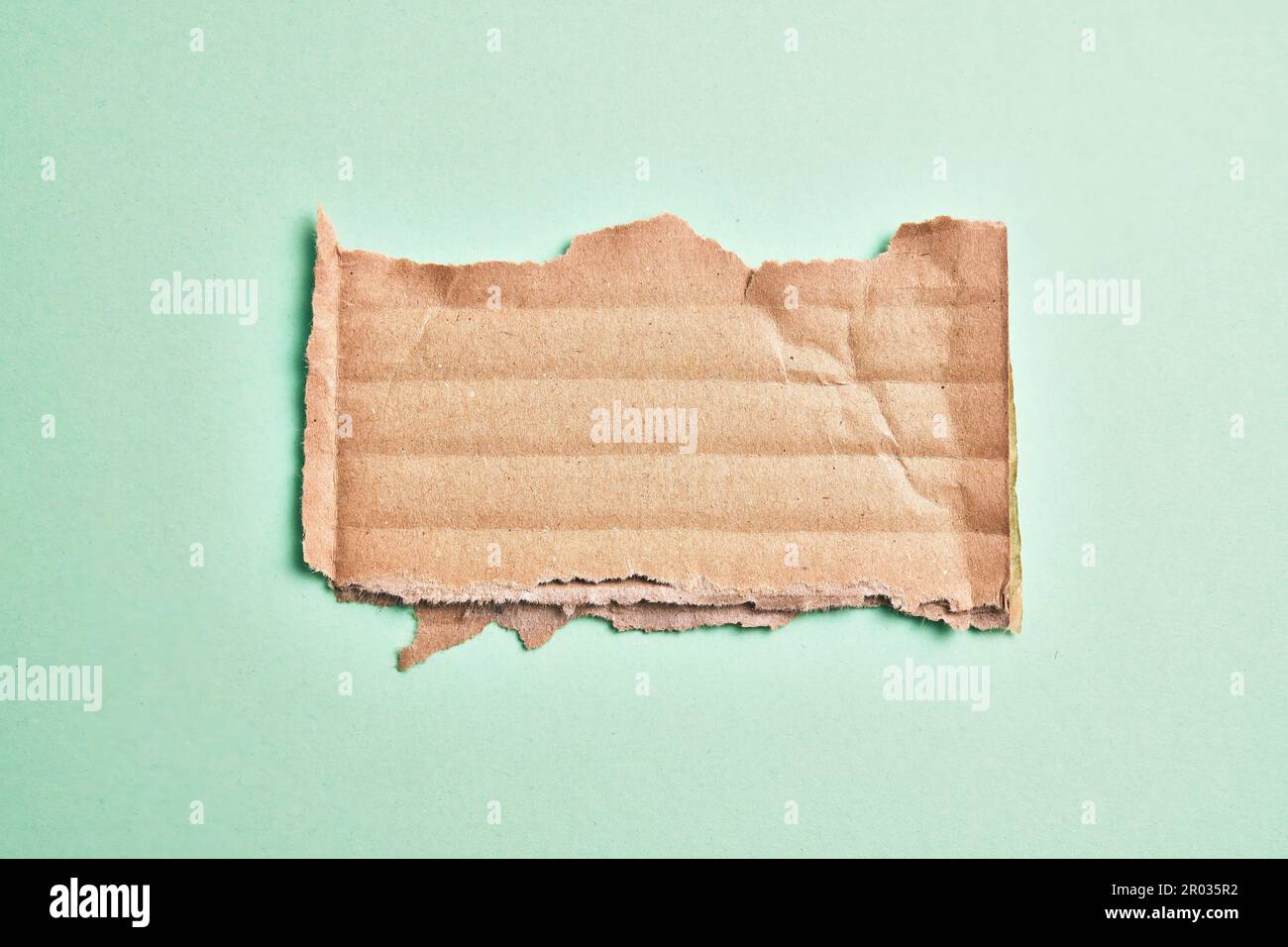 One ripped piece of cardboard material over isolated green background ...