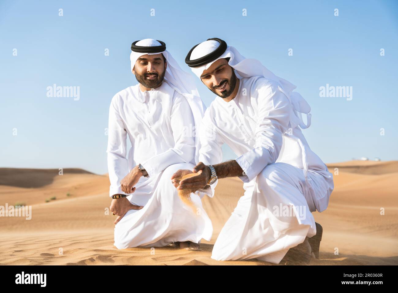 Two middle-eastern men wearing traditional emirati arab kandura bonding ...