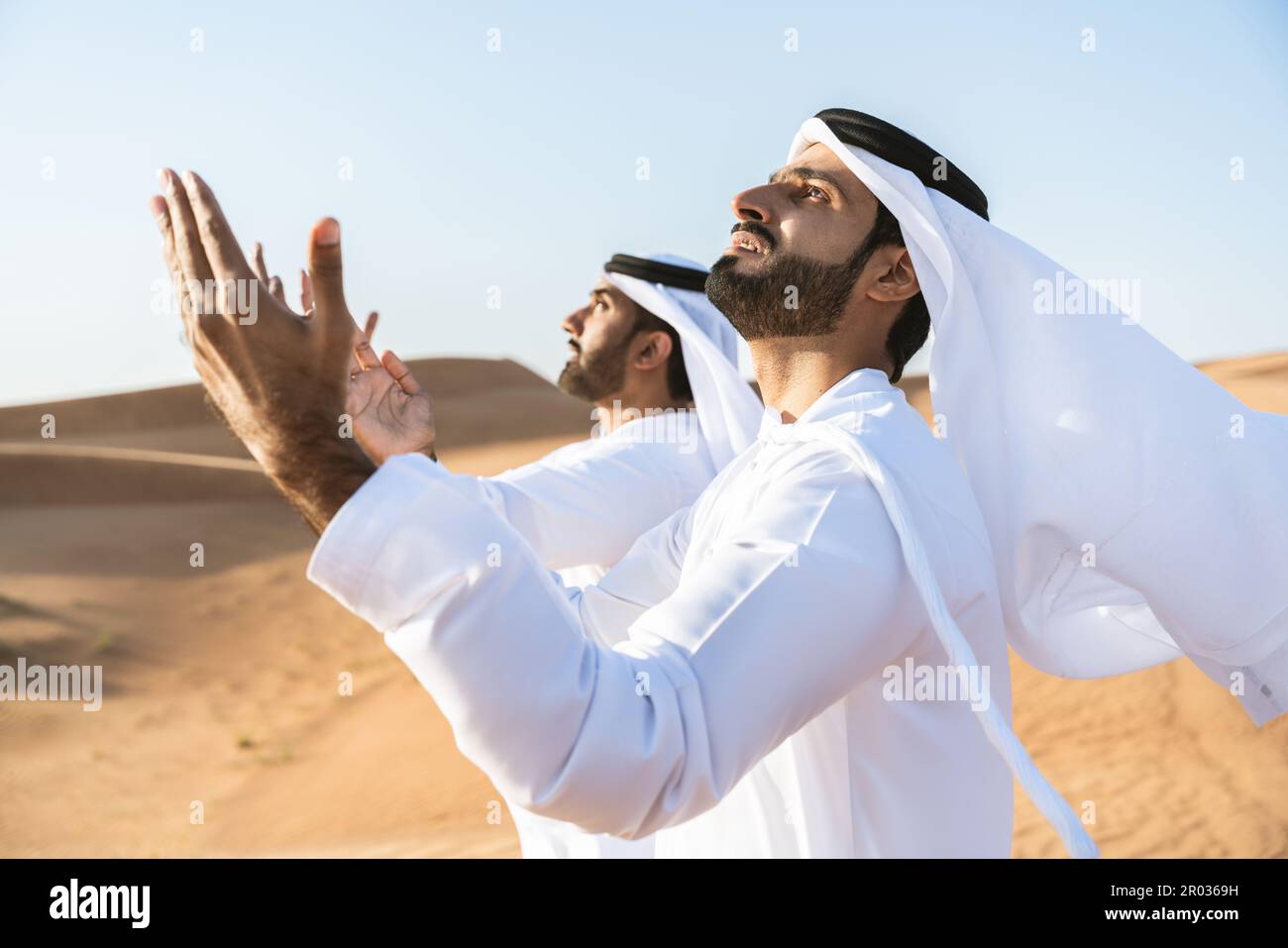 Two middle-eastern men wearing traditional emirati arab kandura bonding ...