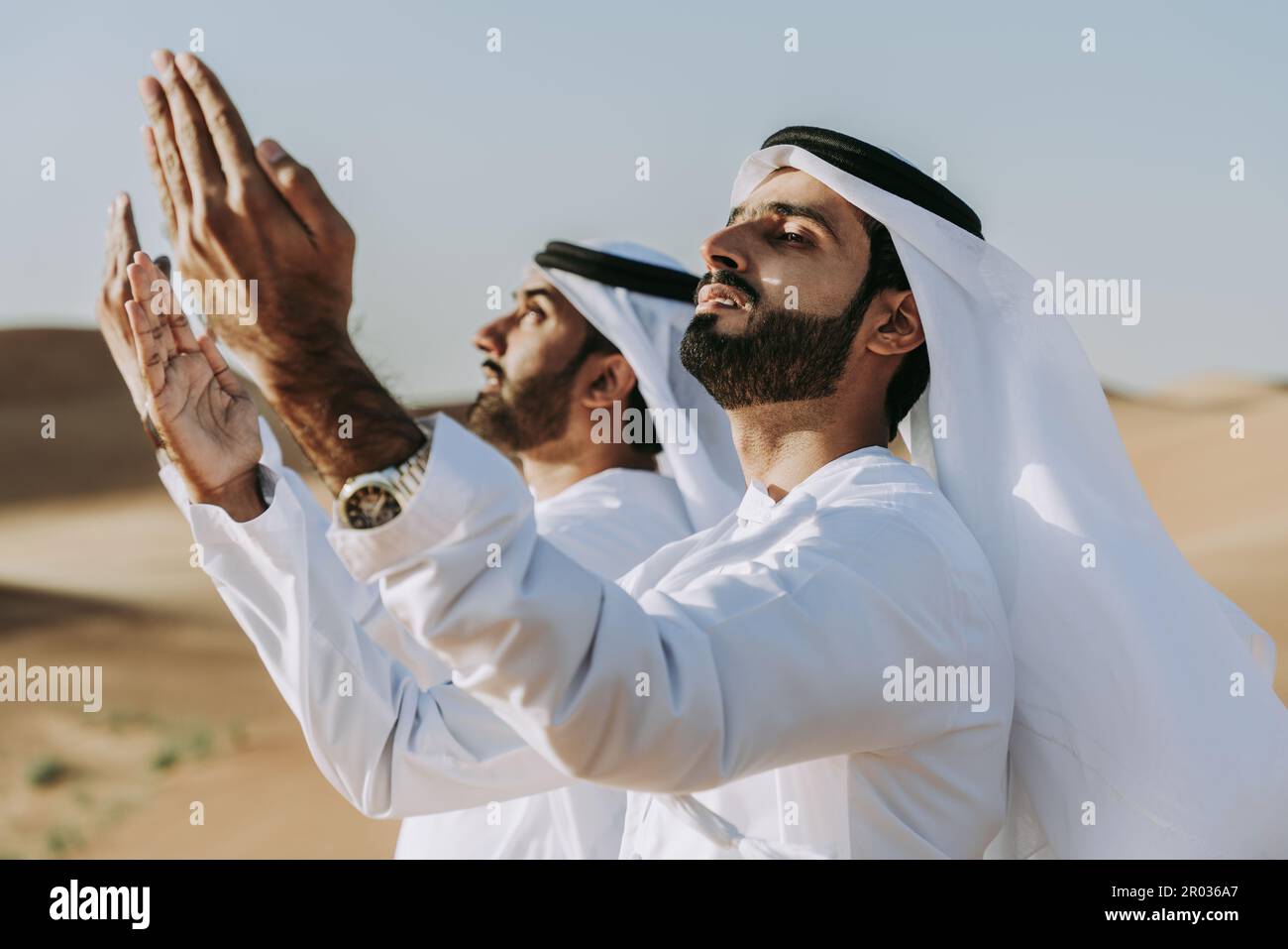 Two middle-eastern men wearing traditional emirati arab kandura bonding ...