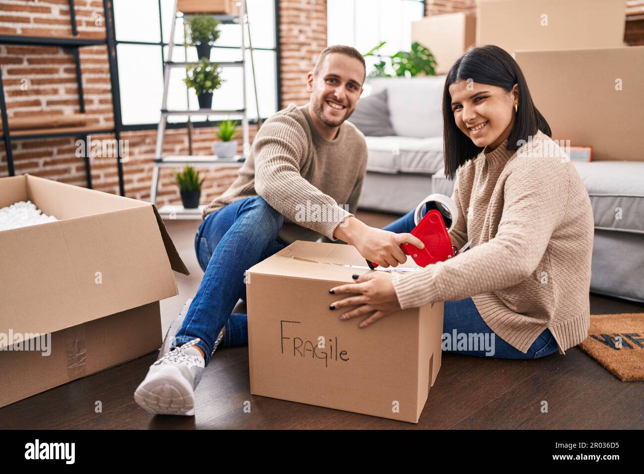 Man and woman couple packing fragile cardboard box at new home Stock Photo - Alamy