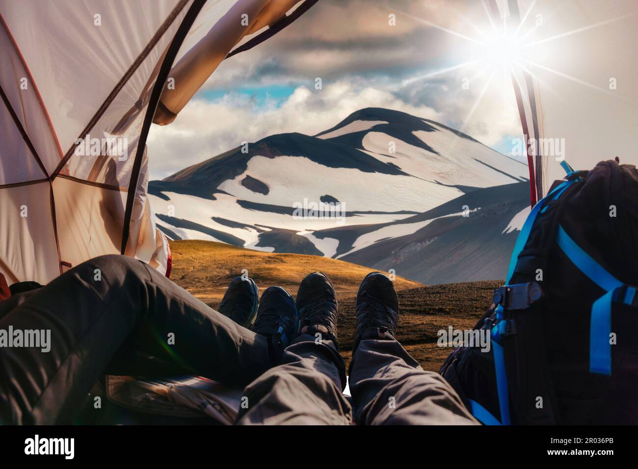 Legs of couple traveler relaxing inside a tent with volcanic mountain ...