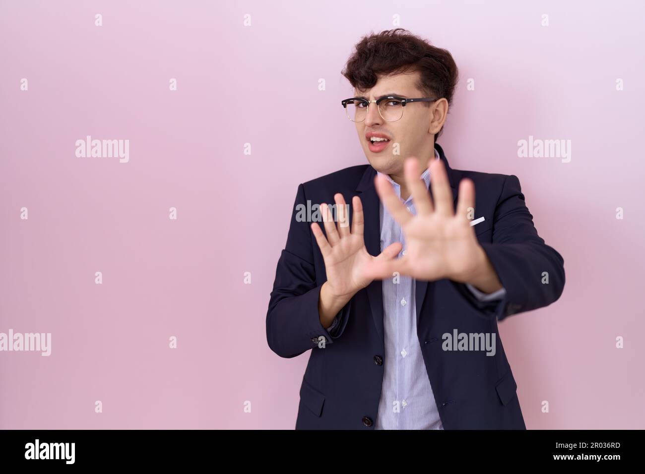 Young non binary man with beard wearing suit and tie afraid and ...