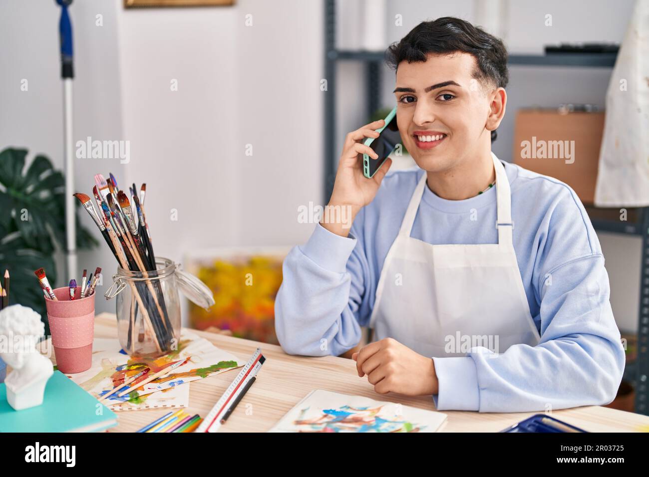 Young non binary man artist smiling confident talking on the smartphone ...