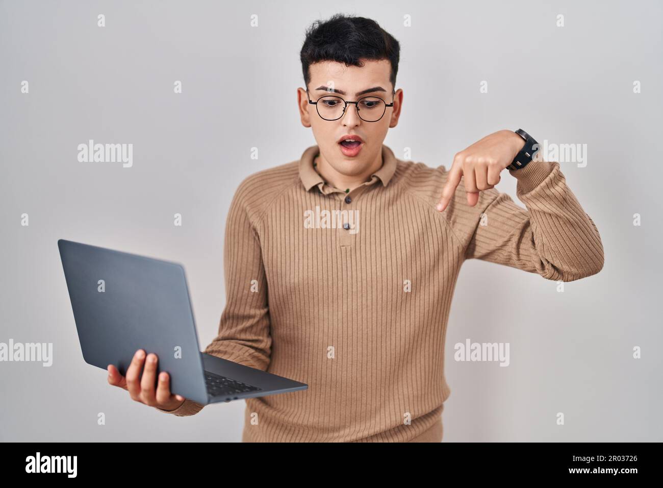 Non binary person using computer laptop pointing down with fingers ...