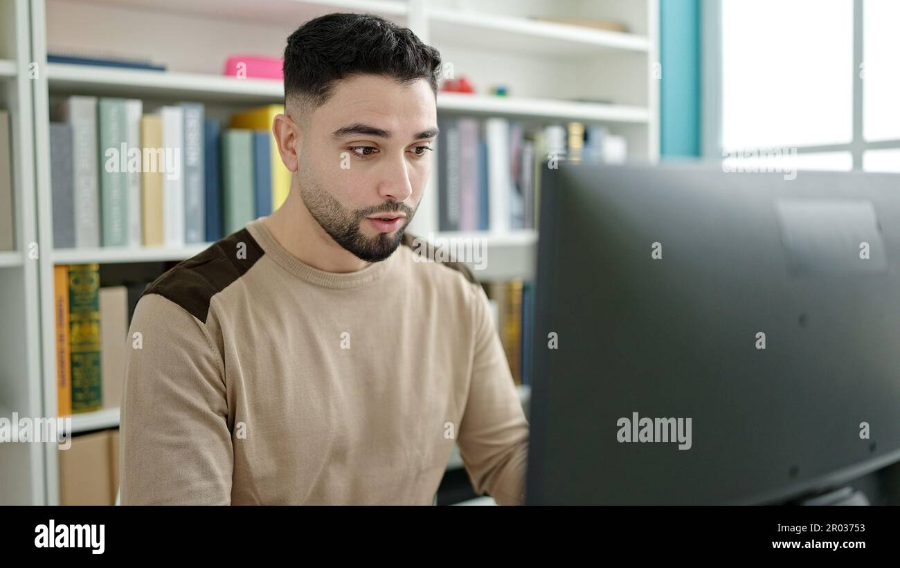 Young arab man student using computer studying at university classroom ...