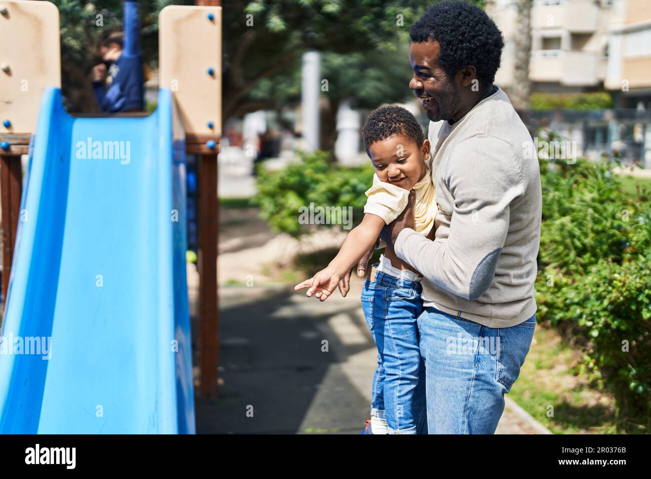 Father and son playing on slide at playground Stock Photo - Alamy