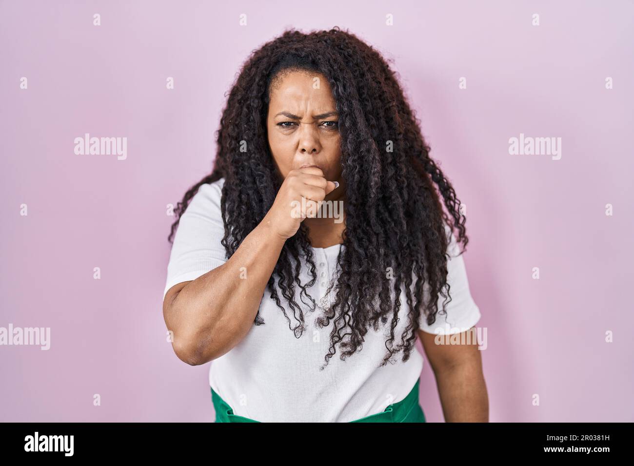 Plus size hispanic woman standing over pink background feeling unwell ...