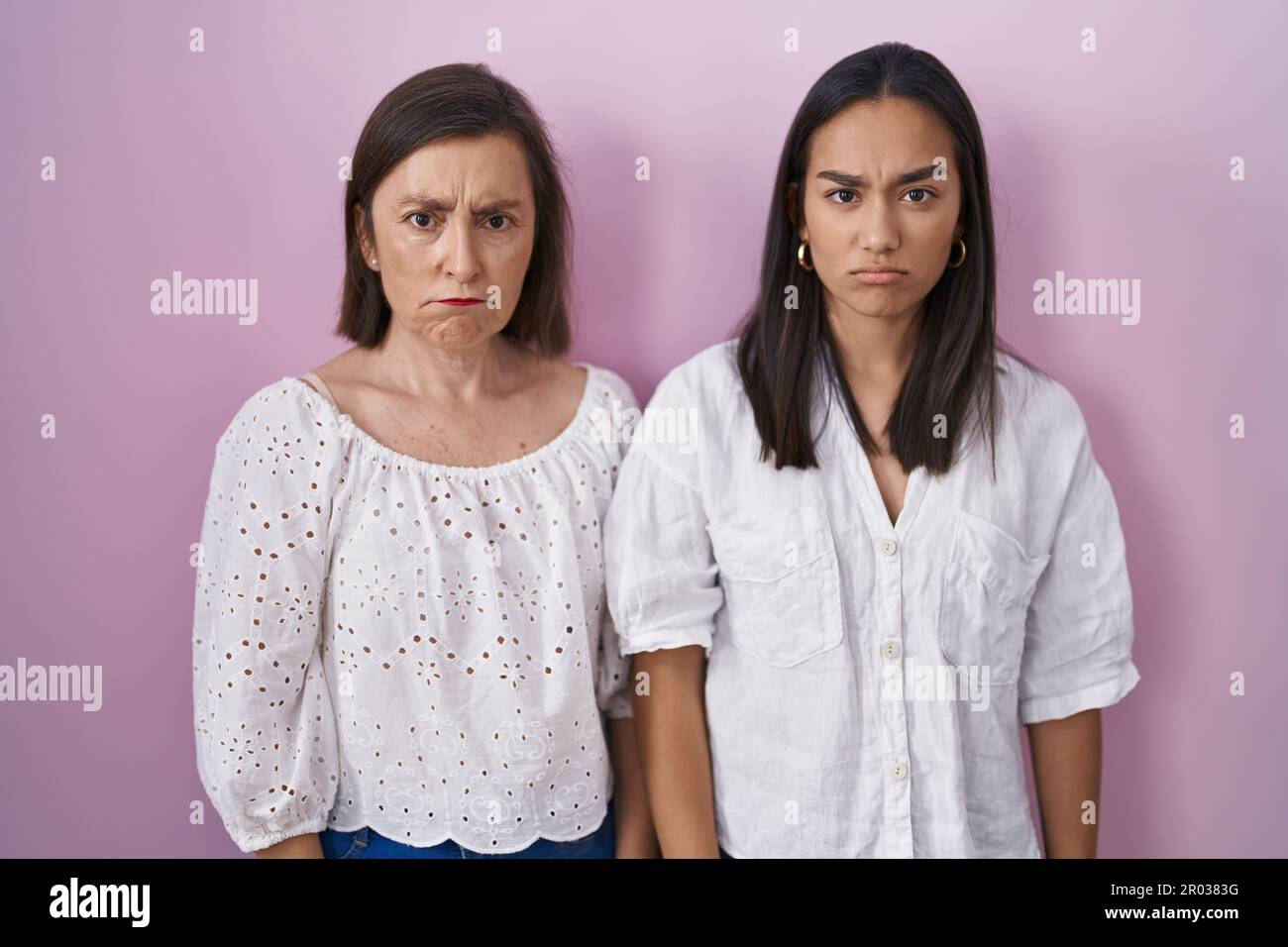 Hispanic mother and daughter together skeptic and nervous, frowning ...