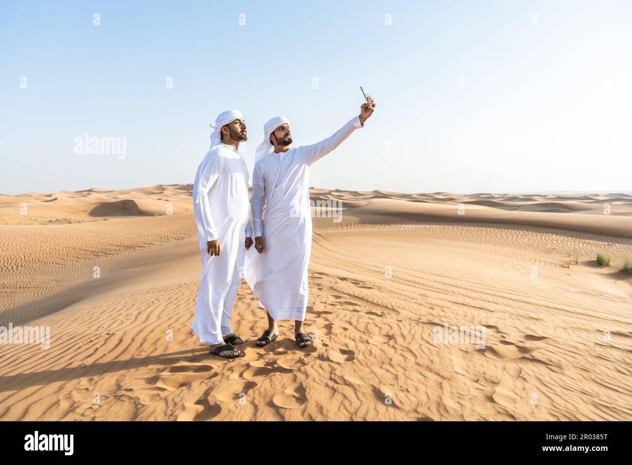 Two middle-eastern men wearing traditional emirati arab kandura bonding ...