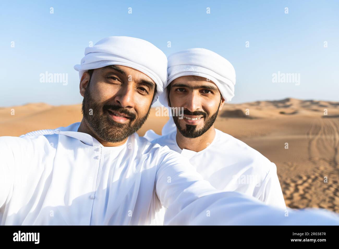 Two middle-eastern men wearing traditional emirati arab kandura bonding ...