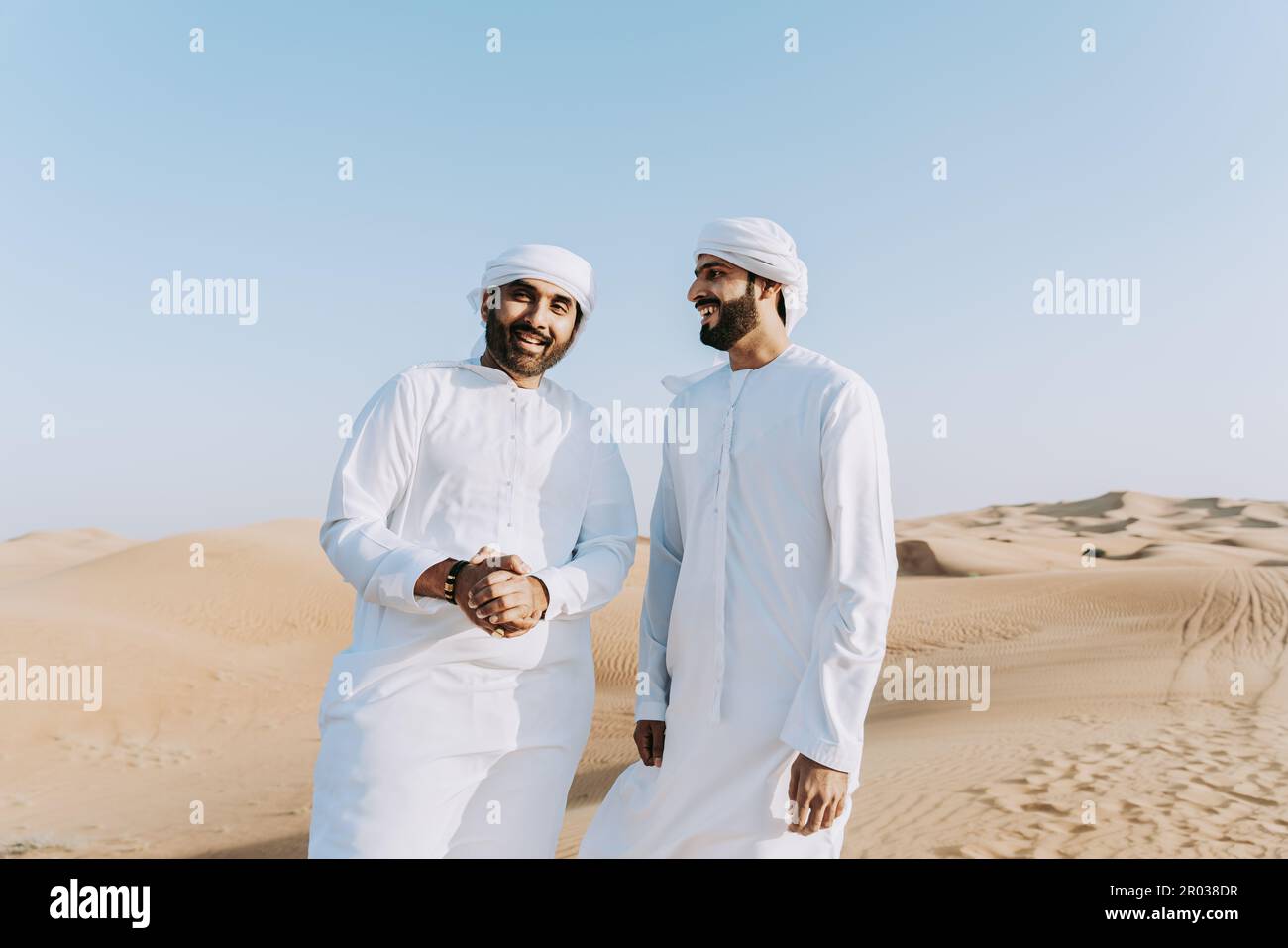 Two middle-eastern men wearing traditional emirati arab kandura bonding ...