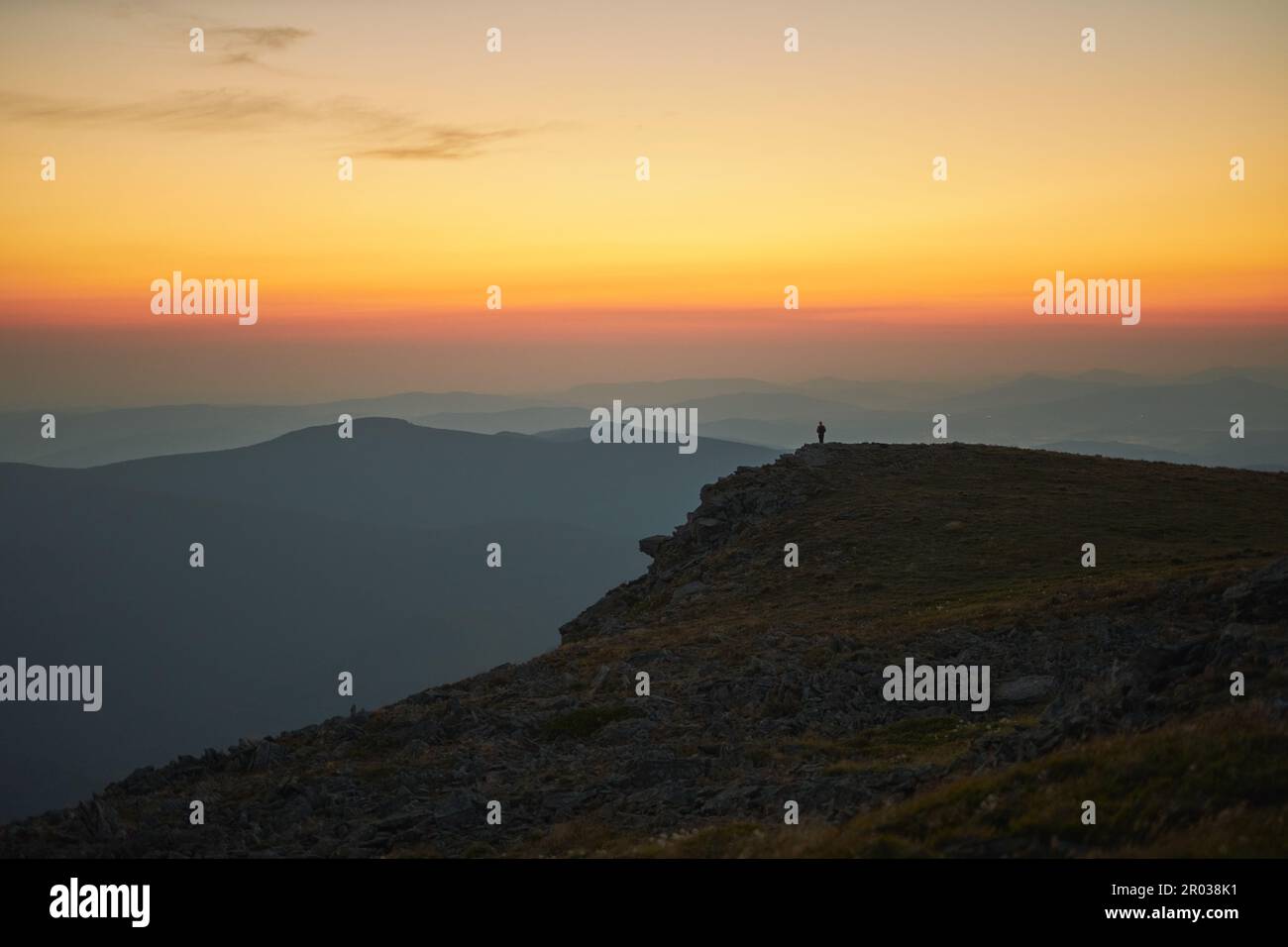 Man looking at sunrise. Mountains at sunrise. Man standing on peak ...