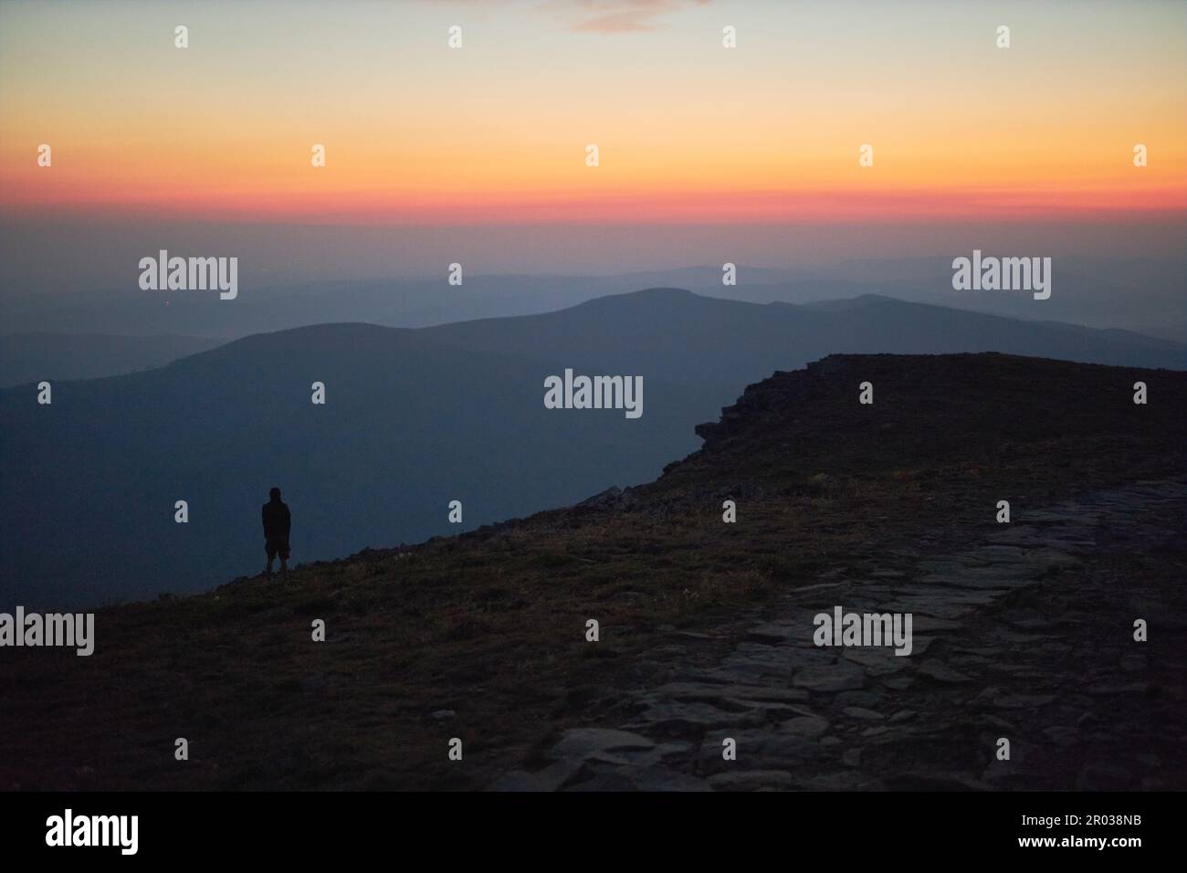 Man looking at sunrise. Mountains at sunrise. Man standing on peak ...