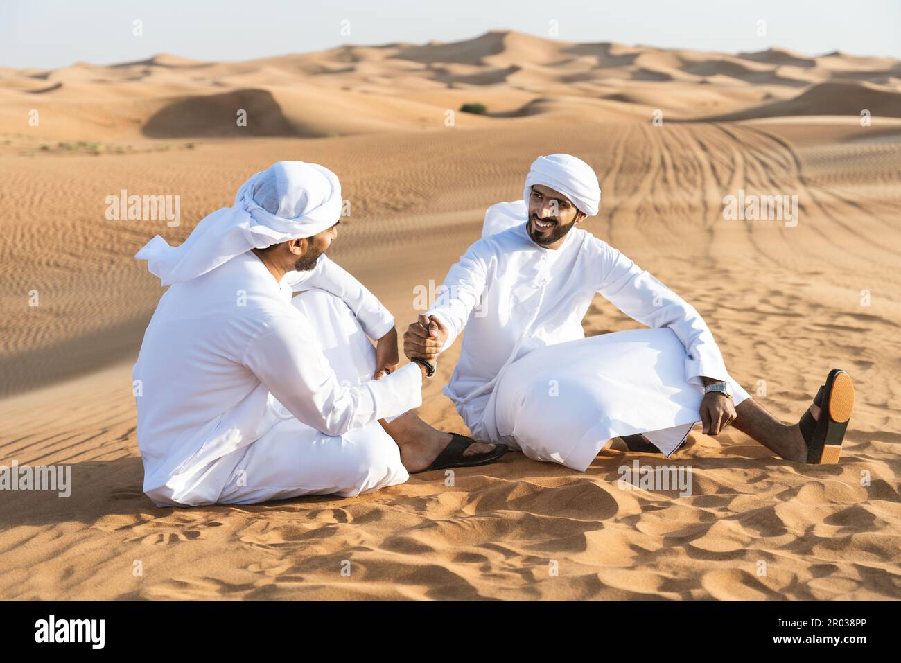 Two middle-eastern men wearing traditional emirati arab kandura bonding ...