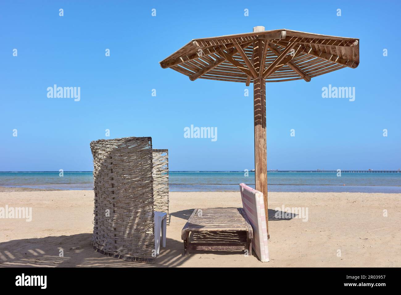 Wooden sun umbrella, sunbed and windscreen on beach Stock Photo - Alamy