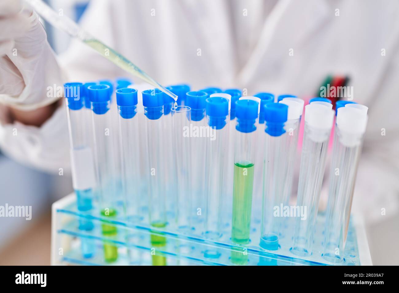 Young woman scientist pouring liquid on test tubes at laboratory Stock ...