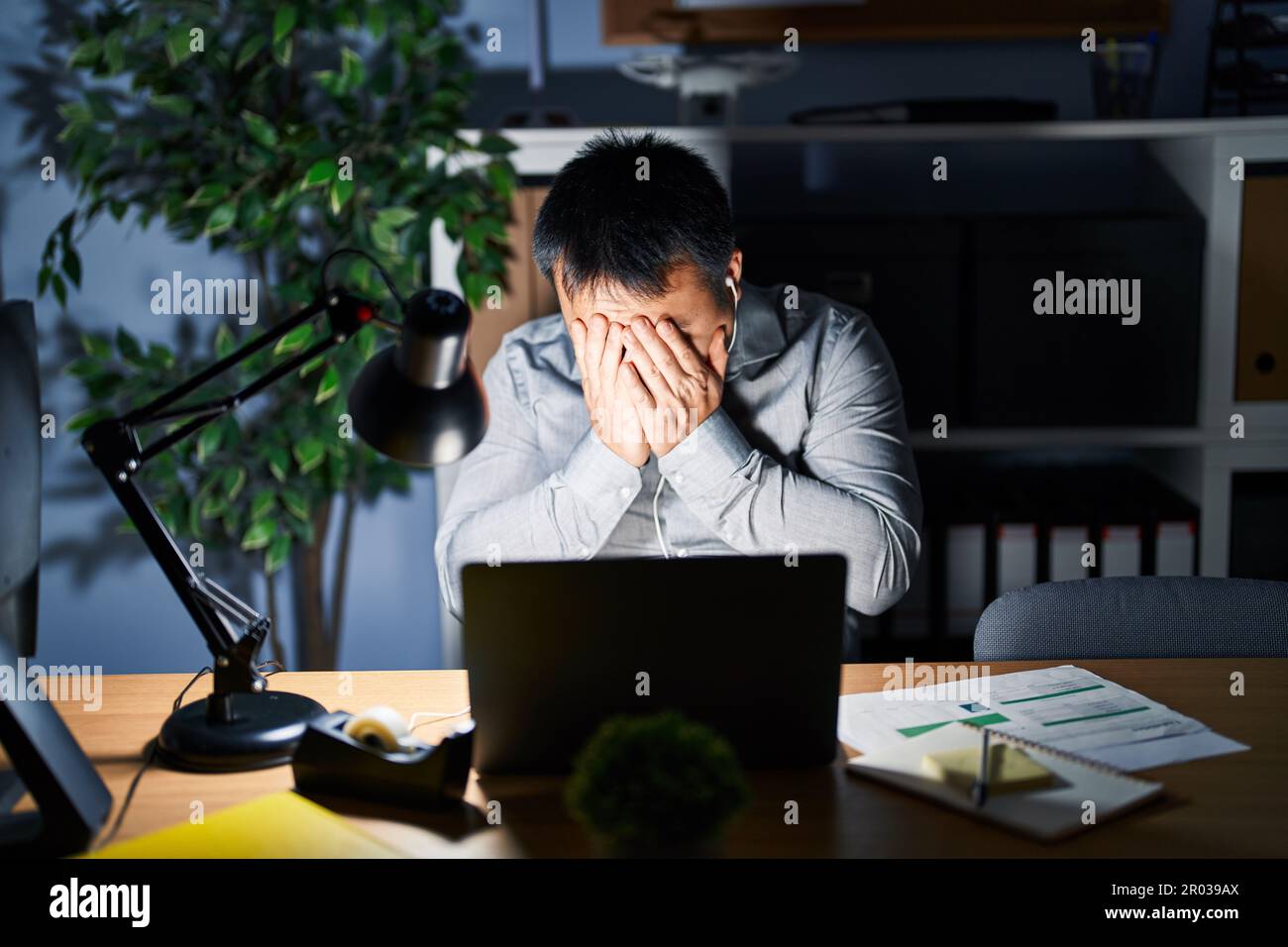 Young chinese man working using computer laptop at night with sad ...