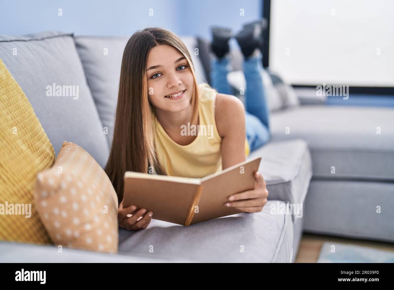 Adorable girl reading book lying on sofa at home Stock Photo - Alamy