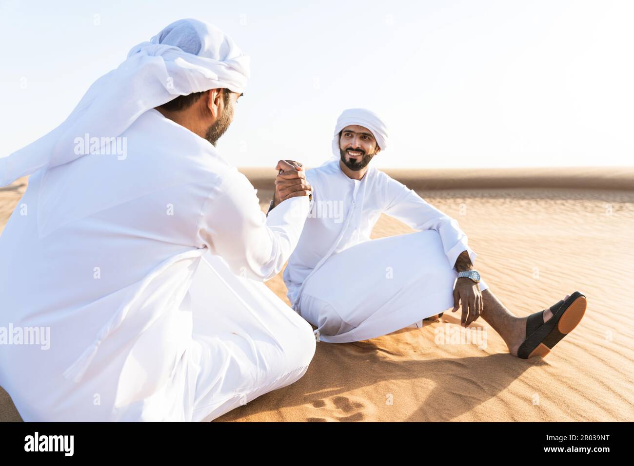 Two middle-eastern men wearing traditional emirati arab kandura bonding ...