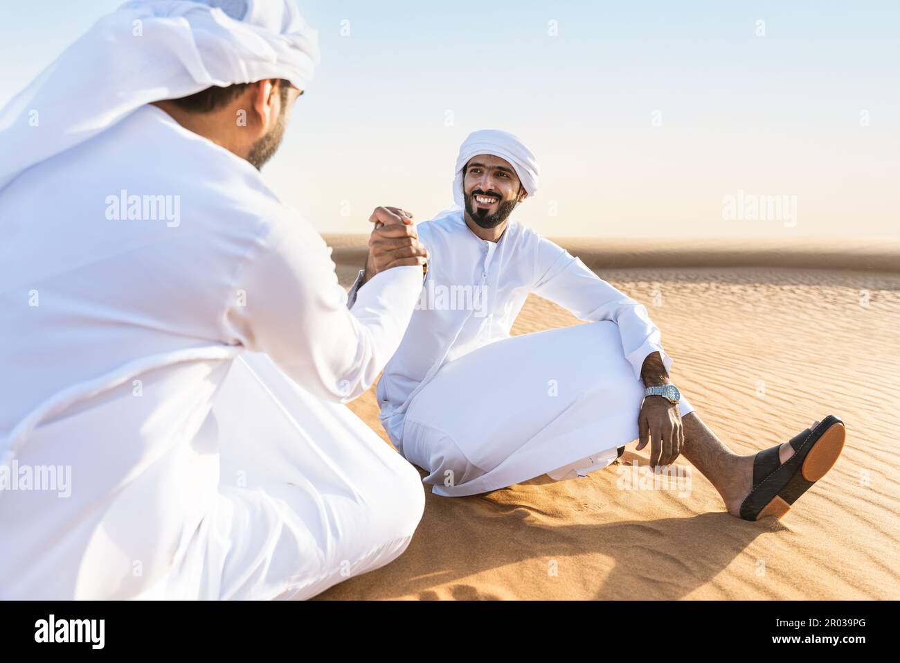 Two middle-eastern men wearing traditional emirati arab kandura bonding ...
