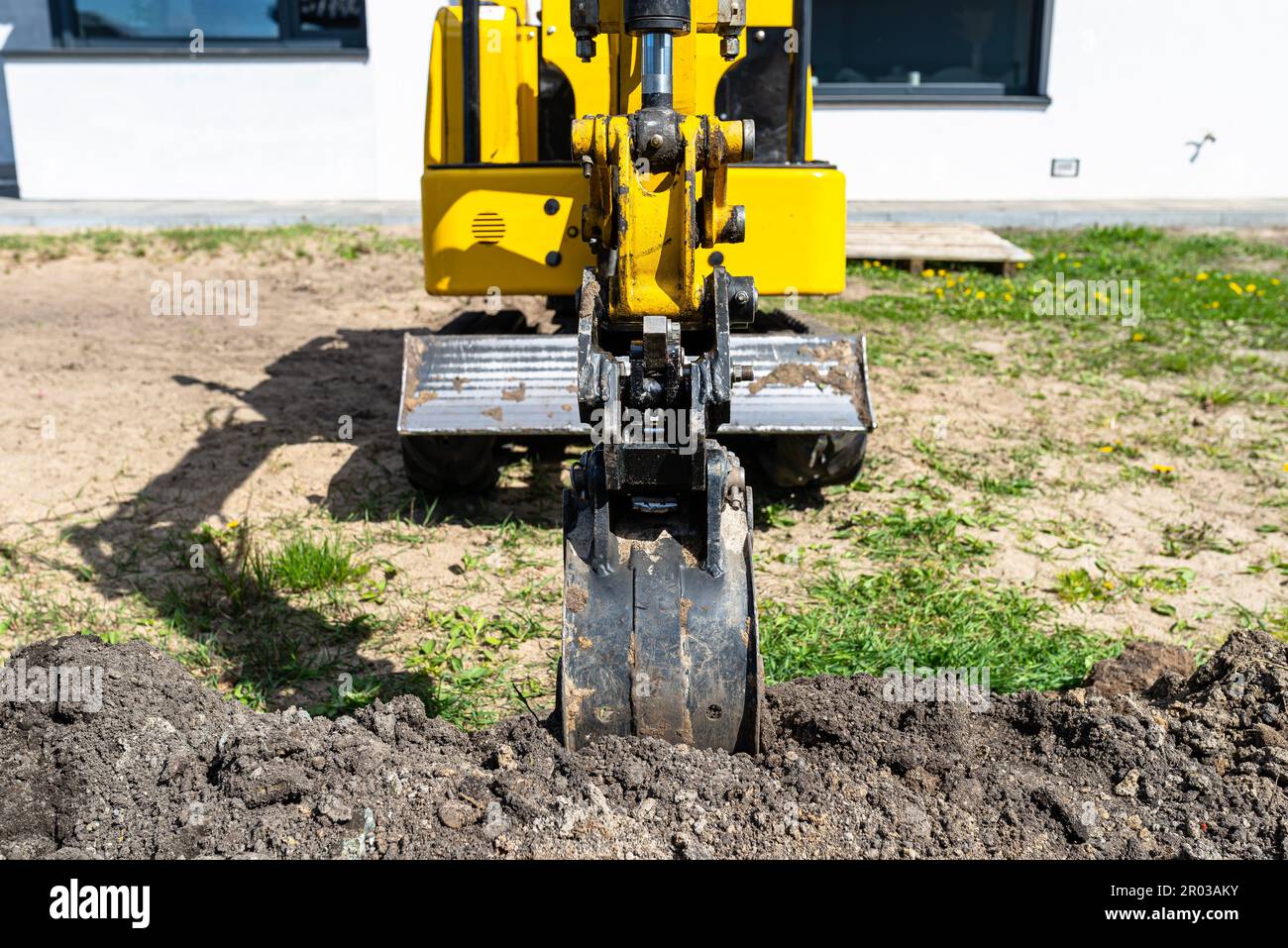 Mini digger digging a hole in the garden along the fence to the ...