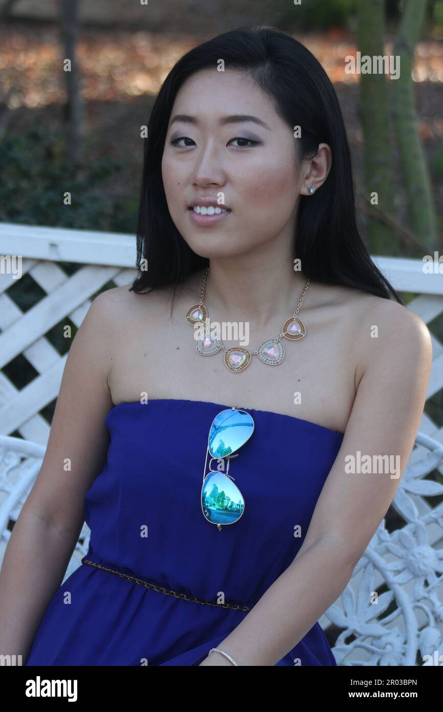 Photo of a pretty Chinese girl in a blue dress seated on a bench Stock ...