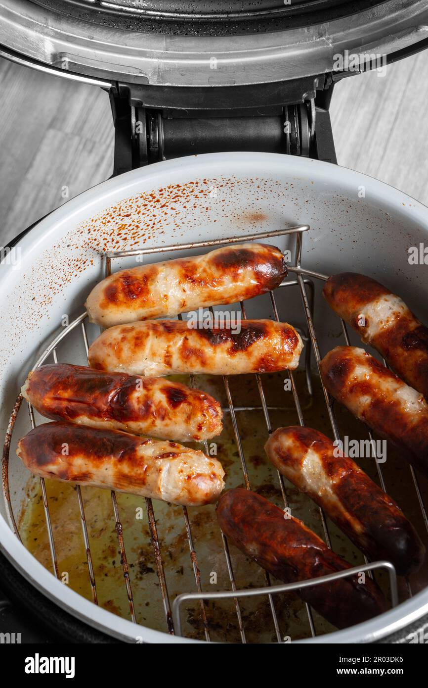 Pork sausages on a rack cooked in an air fryer. Healthy low cost ...