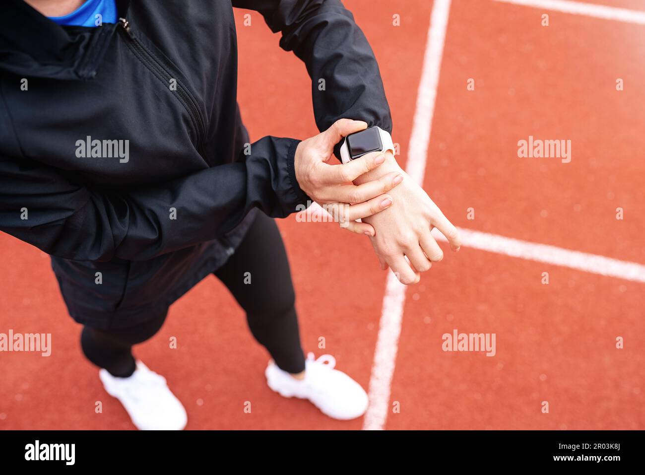 Athlete female person standing on running tracks and using her digital ...