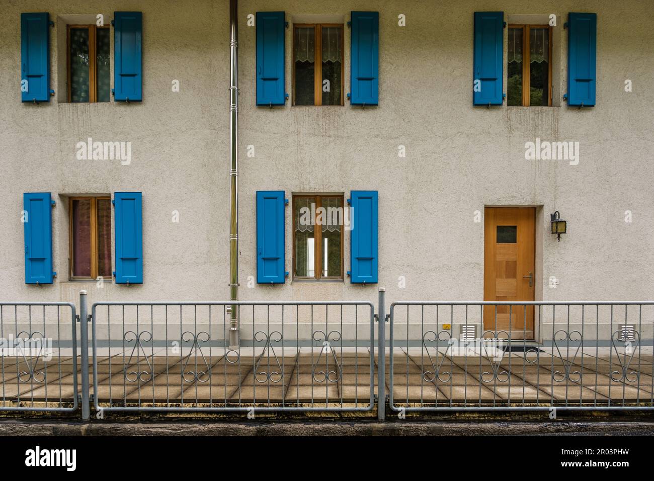 Exterior of a building with five windows with open blue shutters and a ...