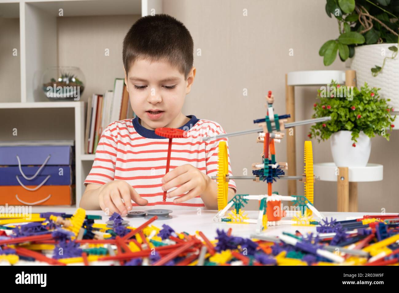 A little boy plays with a constructor, creating figures from gears and ...
