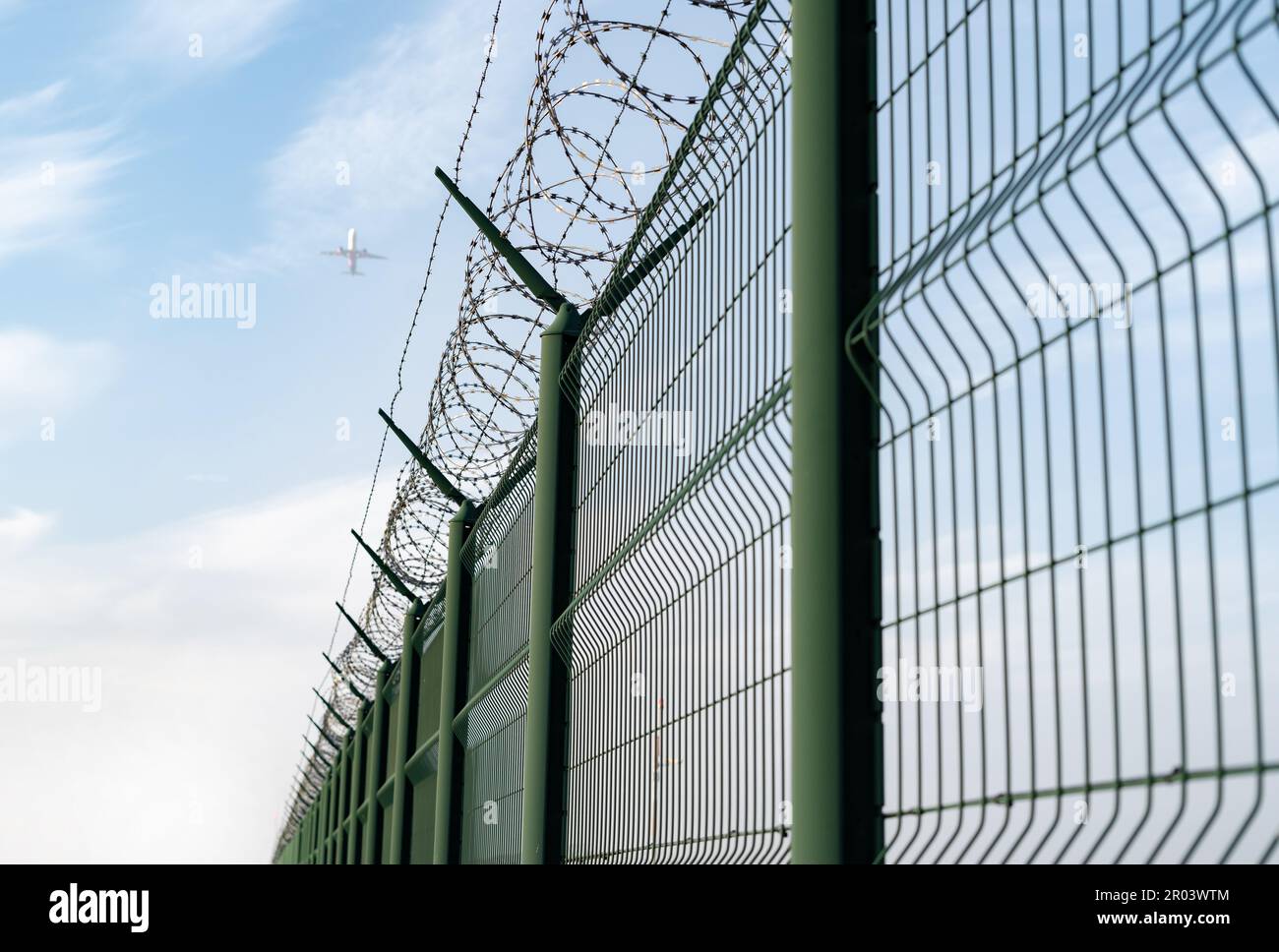 Barbed wire fence at the airport. Green fence. Airplane in the ...