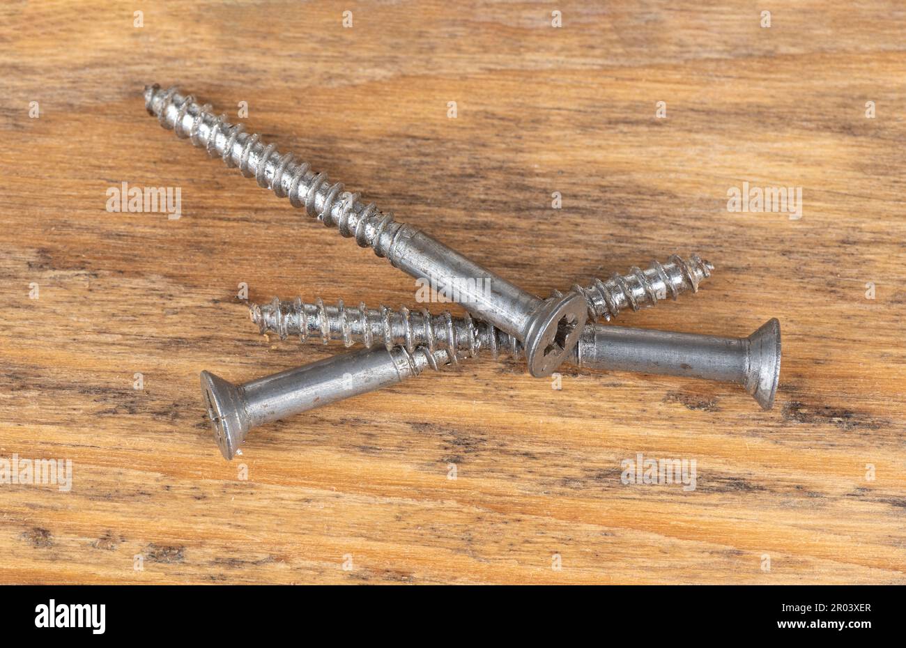 Top view of three steel screws on a wooden background. Self-tapping ...