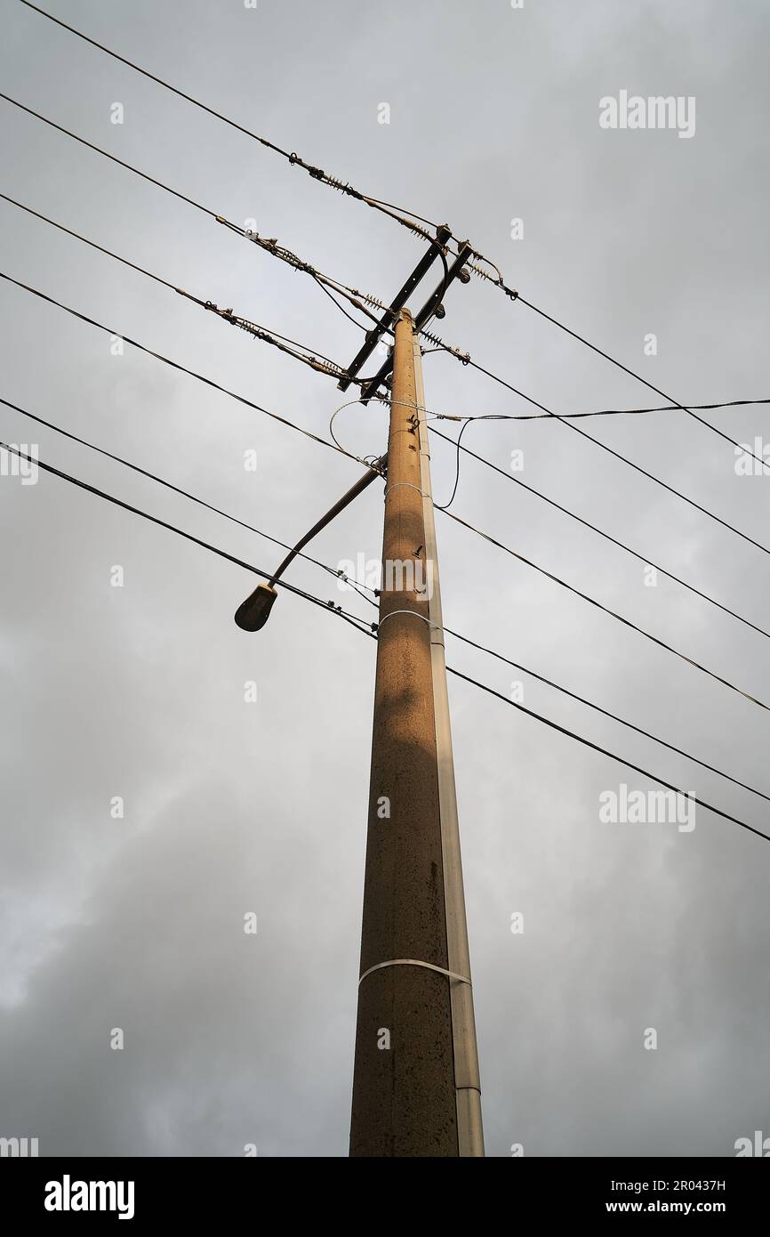 A low-angle shot of the tall electric pole with a bundle of thin ...