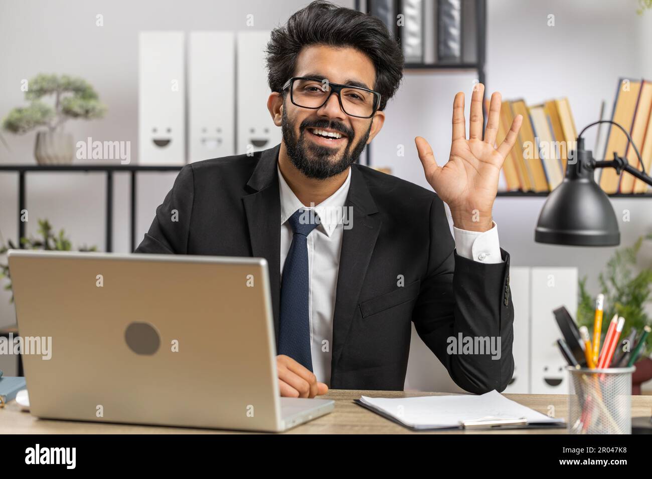 Hello. Indian business man working on laptop computer smiling friendly ...