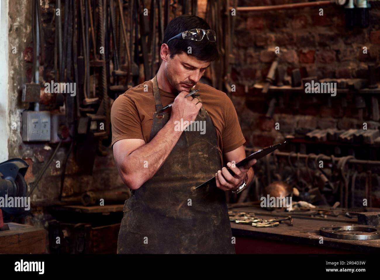 This needs some careful thinking. a handsome young craftsman using a digital tablet while ...