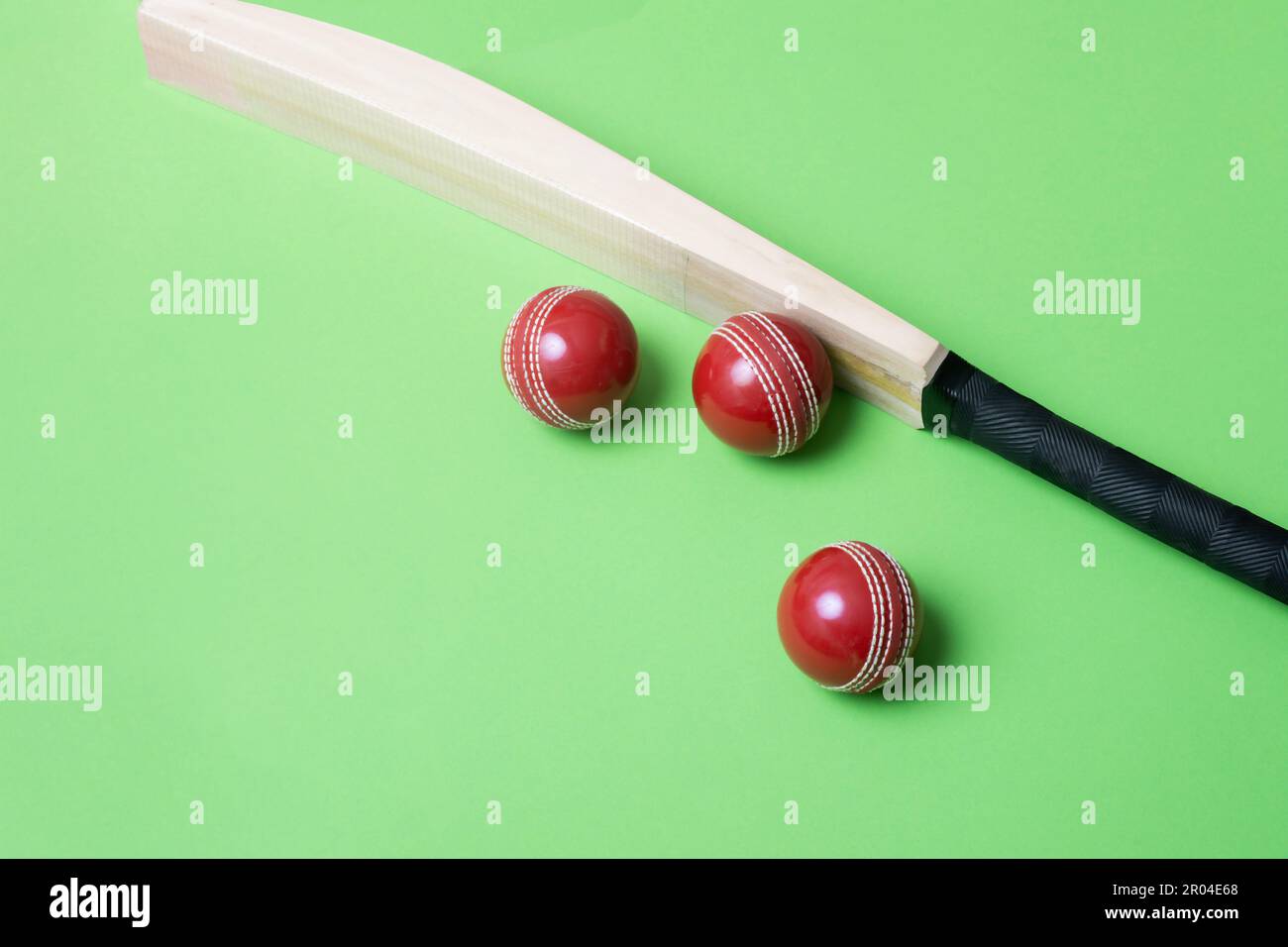 Cricket bat and red balls on green background. Horizontal sport theme ...