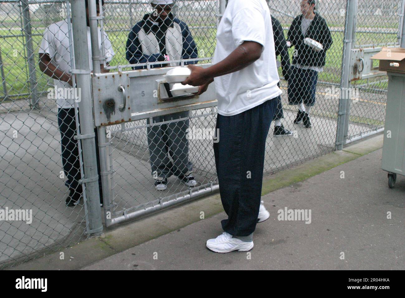 A smiling man stands in front of a white picket fence with an arm full ...