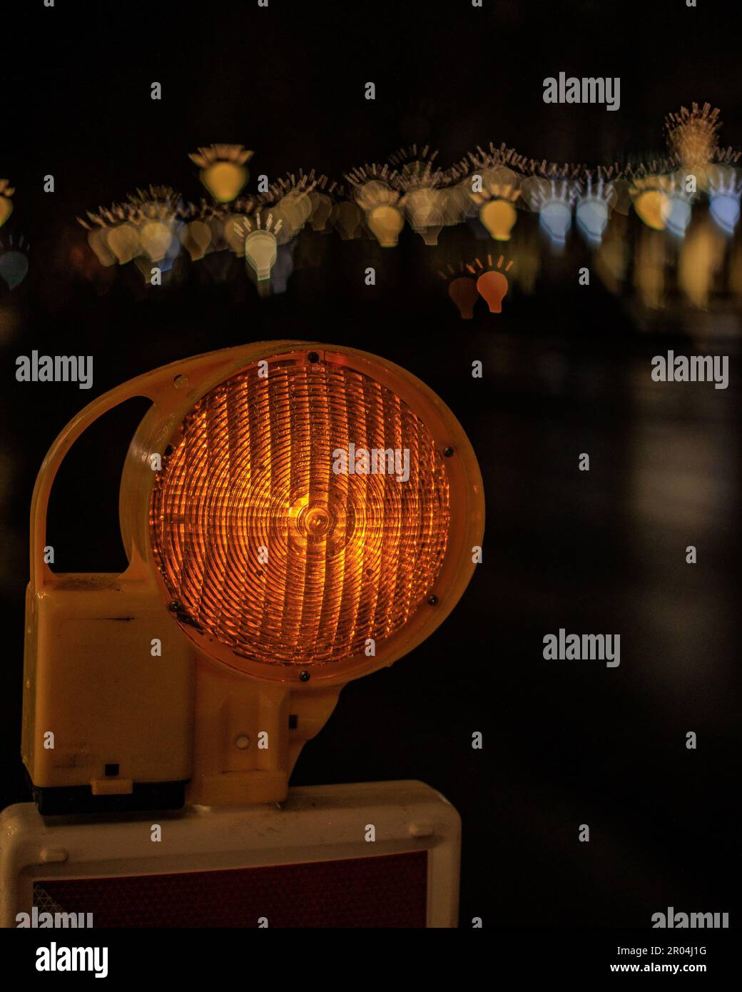 A yellow traffic signal illuminated from atop an overpass, with a ...