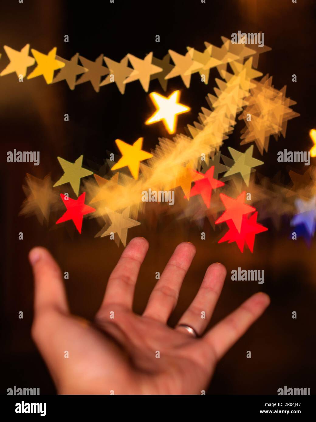A hand, with stars cascading across its fingertips, against a backdrop ...