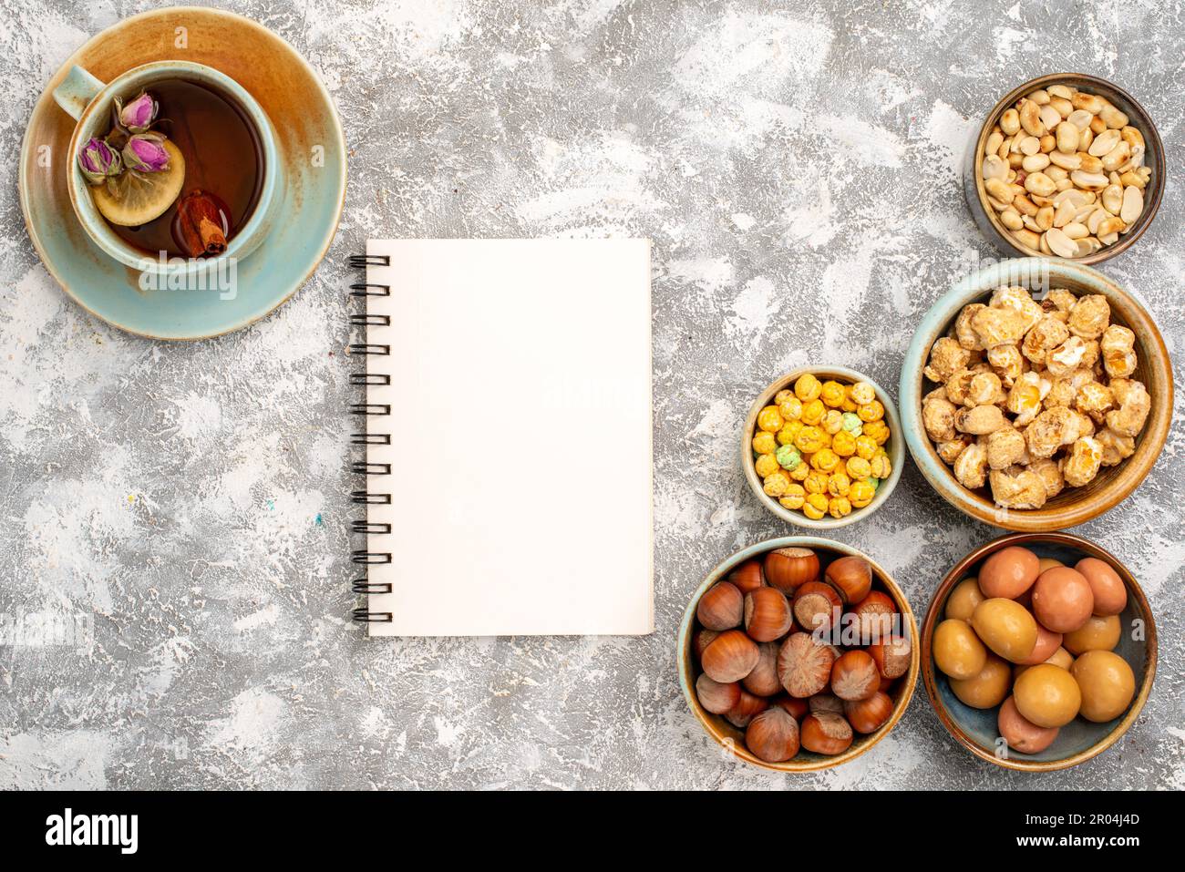 top view cup of tea with nuts notepad and candies on white background ...