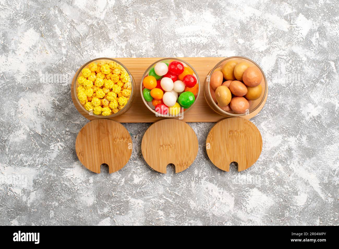 top view different candies colored inside little glasses on white ...
