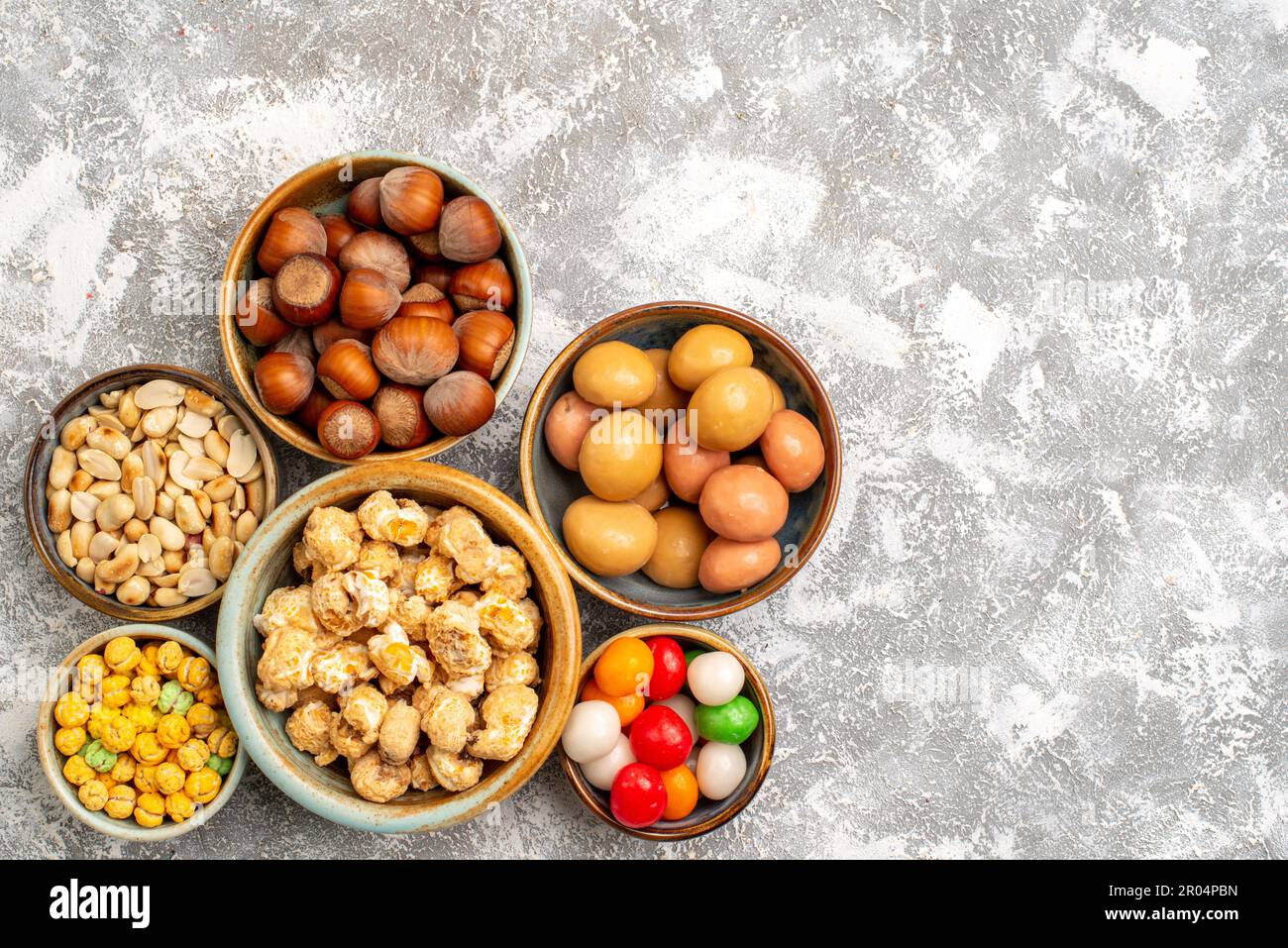 top view hazelnuts and peanuts with candies on the white background nut ...