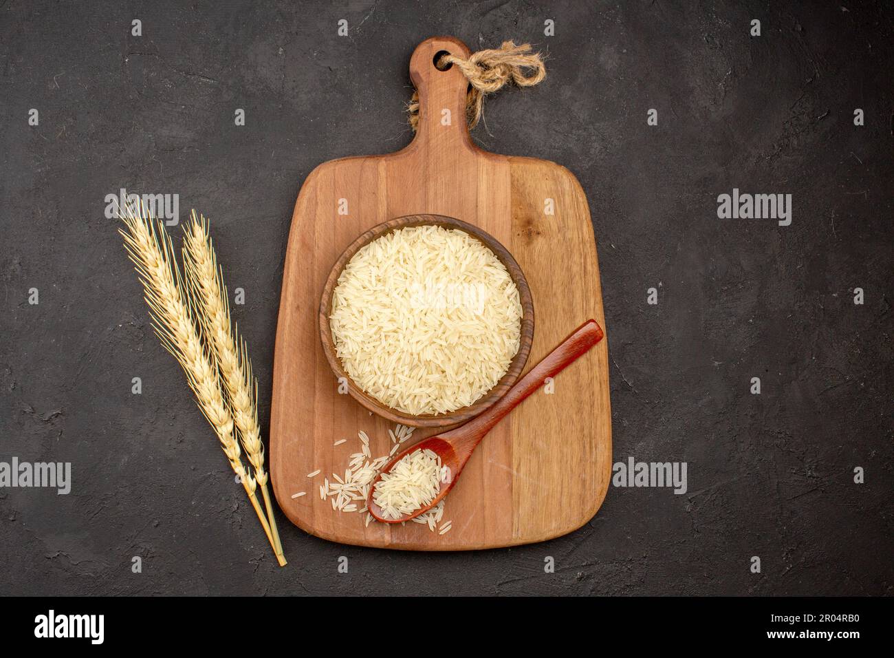 top view raw rice inside wooden brown plate on dark grey background ...