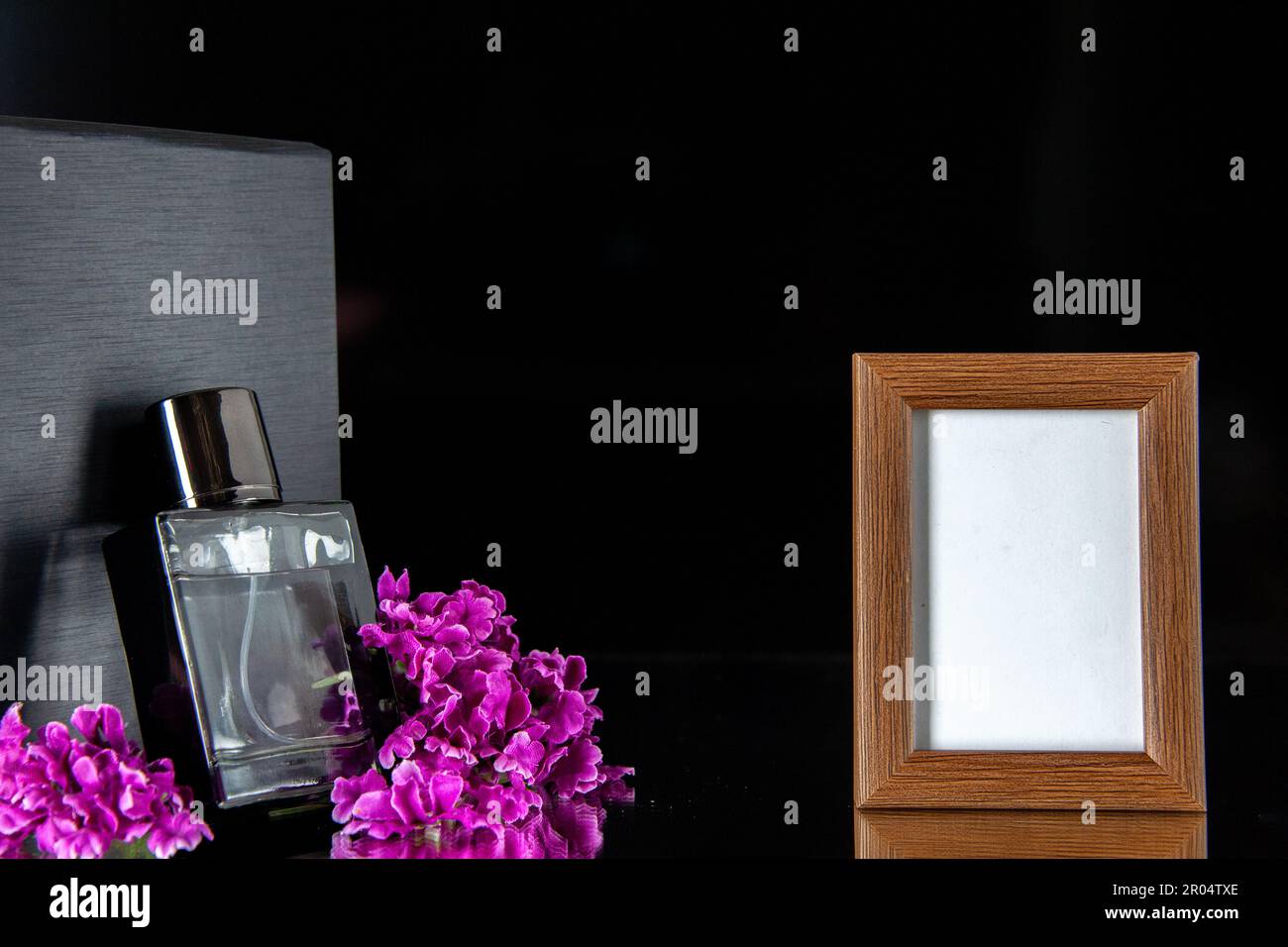 front view black expensive fragnance with picture frame on black ...